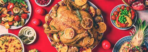 새해 저녁 식사 테이블입니다 오렌지 슬라이스 크랜베리 마늘 축제 장식 양초 귤 석류 붉은 배경에 황금 반짝이 별 구운 크리스마스 치킨 상단 보기 복사 공간 추수감사절에 대한