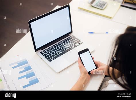 Woman S Hands Using Mobile Phone And Laptop At The Office Stock Photo