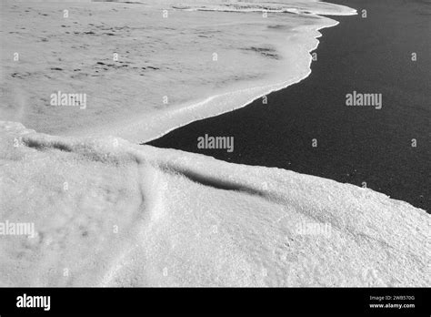 Mostly Blurred Black Sand Beach With White Foam Of Sea Waves Background