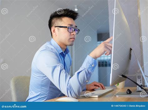 Young Asian Male Programmer Wearing Shirt And Glasses Working While