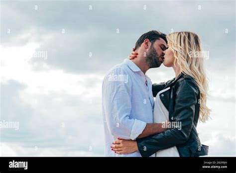 Attractive Woman And Handsome Man Huggingand Kissing Outside Stock