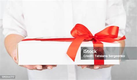 빨간 활이 달린 흰색 선물 상자를 들고있는 여성 손의 클로즈업 여자는 빨간 리본이 달린 흰색 상자를 들고 있습니다 기념일에 대한 스톡 사진 및 기타 이미지 Istock