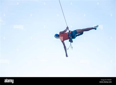 View Of Man In Hardhat Hanging On Rope While Doing Rappel And Showing Pirouettes Flying In Air