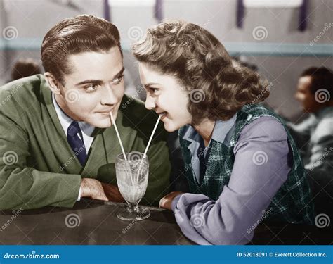 Couple In A Restaurant Looking At Each Other And Sharing A Milk Shake