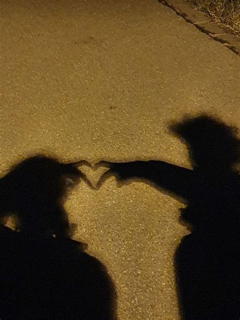 Two People Standing Next To Each Other In The Street With Their Shadows