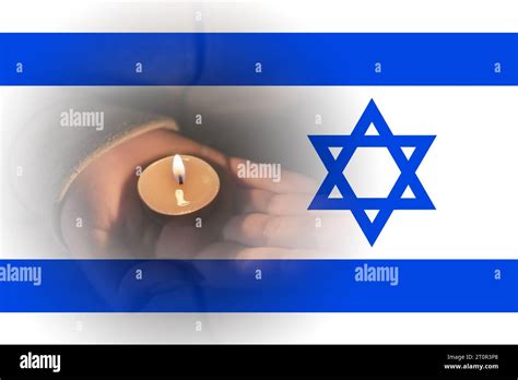 A Burning Candle In Hands Against The Background Of The Israeli Flag