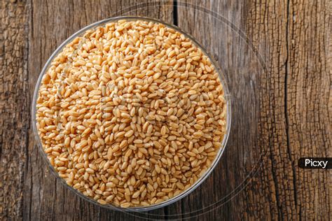 Image Of Wheat Grains In A Glass Bowl On An Isolated Wooden Background