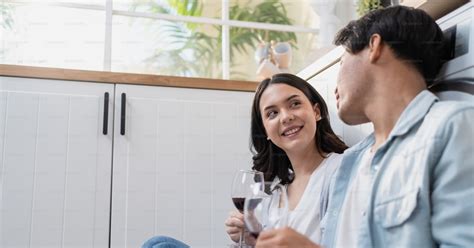 아시아의 젊은 신혼 부부는 집에서 부엌에서 함께 시간을 보낸다 매력적인 낭만적 인 남자와 여자는 가족 관계 생활과 새 집으로 이사하는 것을 축하하기 위해 와인을 마신다