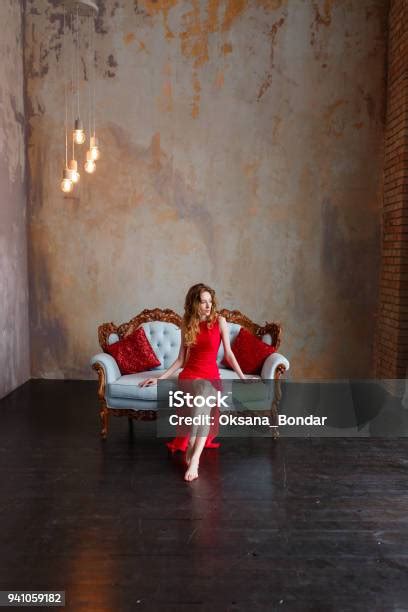 화이트 레트로 가죽 소파에 앉아 최소한의 소박한 로프트 벽의 배경에 놀라운 빨간 드레스에 아름 다운 여자 가정의 방에 대한 스톡 사진 및 기타 이미지 Istock