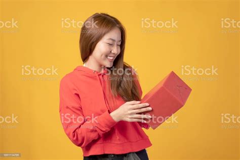 캐주얼 젊은 행복 미소 아시아 여성의 초상화선물 상자를 개최합니다 노란색 배경 위에 빨간 선물 상자를 들고 아름다운 젊은 아시아 소녀 유쾌한 흥분 얼굴선물 상자를 들고 빨간