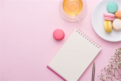 Flatlay 노트북 마카롱 차와 꽃 분홍색 테이블에 컵 케이크 아름 다운 아침 식사와 함께 마 카 롱입니다 모형에 대한 스톡