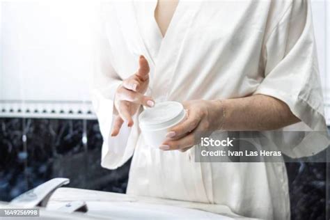 목욕 가운을 입은 알아볼 수 없는 여성의 초상화는 병에서 크림을 집어 들고 바디 케어와 아름다움의 신체 개념에 적용합니다 20