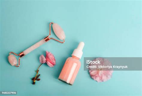세럼 병 페이스 롤러 분홍색 사쿠라가 파란색 배경에 꽃을 피운다 피부 관리 뷰티 트리트먼트 개념 평면도 평면도 복사 공간 벚꽃에