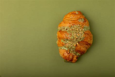 녹색 질감 배경에 신선한 크로와상 피스타치오 껍질을 곁들인 수제 맛있는 크로와상 텍스트를 위한 공간입니다 복사할 장소 플랫 레이