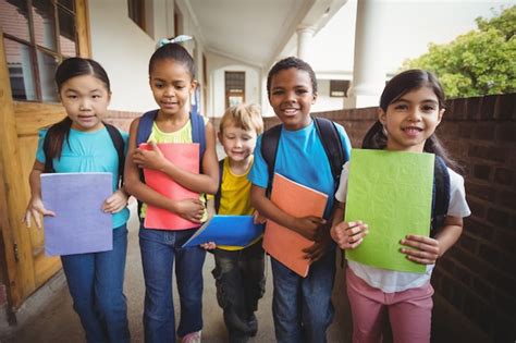 Premium Photo Cute Pupils Holding Notebooks At Corridor