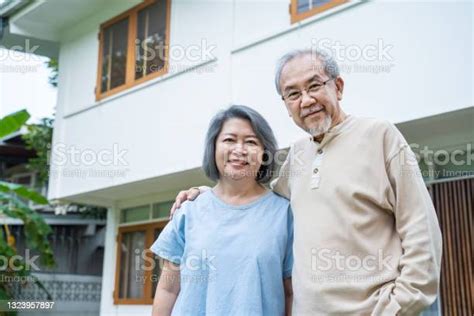 아시아 노인 부부는 집에서 야외에 서서 행복한 느낌과 함께 은퇴 생활을 즐길 수 있습니다 사랑하는 할머니는 미소를 지으며 서로를 껴안습니다 가정 개념의 관계 및 활동 가족에
