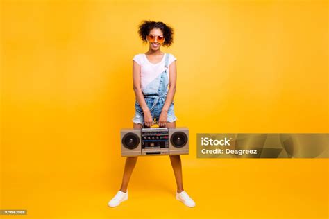멋진 예쁜 소녀의 청바지 낙하산 강 하복 스 니 커 즈 안경 카메라 보고 손에 카세트 테이프와 붐 박스를 들고 전체 크기 세로