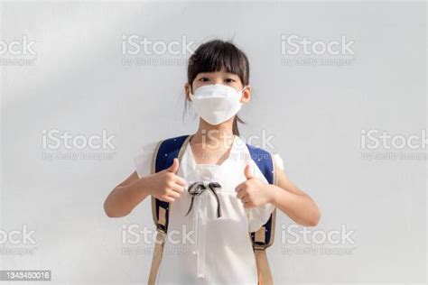 Pm25를 보호하기 위해 마스크를 쓰고 있는 어린 아시아 소녀는 야외에서 좋은 공기를 마시며 엄지손가락을 치켜들고 제스처를 보여