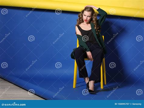 Beautiful Young Woman Sitting On Chair Against Color Background Stock