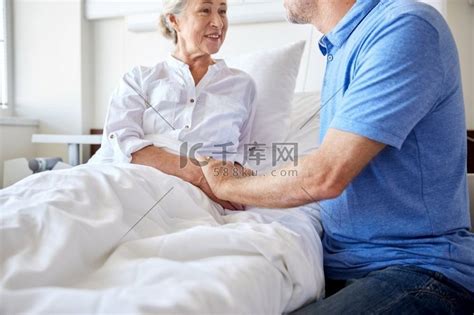 医学、医疗保健和人的概念——快乐的老人探望躺在医院病房床上的女人，并为他的女人欢呼。高清摄影大图 千库网