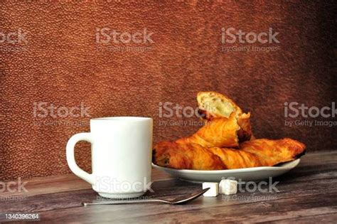 카푸치노 한 컵과 나무 테이블에 구운 고기 만두 두 개가 있는 접시 티스푼과 설탕 2개 구도에 대한 스톡 사진 및 기타 이미지