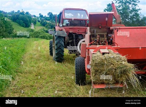 The Process Of Harvesting Hay For Cattle A Tractor Making Bales In The Field Old Machinery