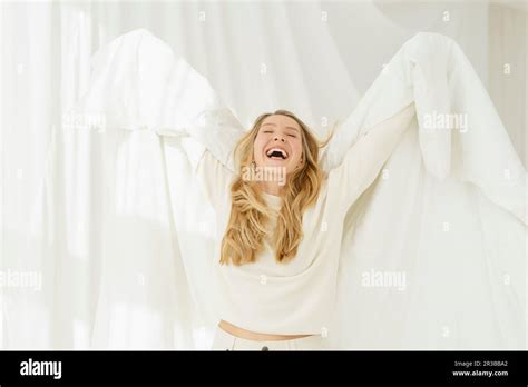 Cheerful Woman With Arms Raised Wearing White Blanket In Front Of