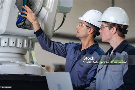 Engineers Programming Large Robotic Arm In Industrial Setting Integration Of Advanced Technology