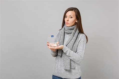 회색 스웨터에 젊은 여자 스카프 회색 벽 배경 스튜디오 초상화에 고립 된 매일 알 약 상자를 들고 건강 한 라이프 스타일 아픈