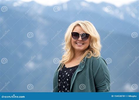 Blonde Woman Wearing Sunglasses Poses For A Portrait With The Cascade