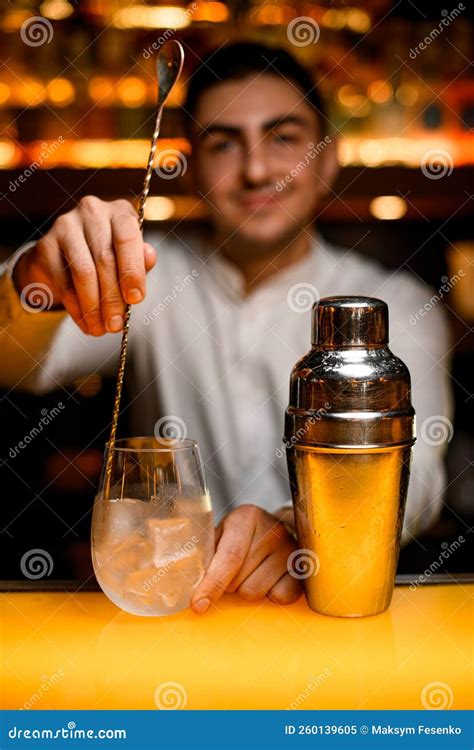 Close Up On Shaker And Bartender Stirring Alcoholic Cocktail With Bar