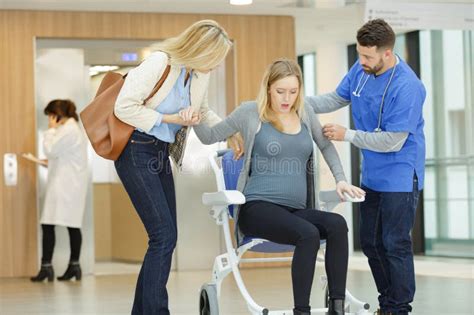 Woman And Doctor Comforting Pregnant Woman In Corridor Hospital Stock