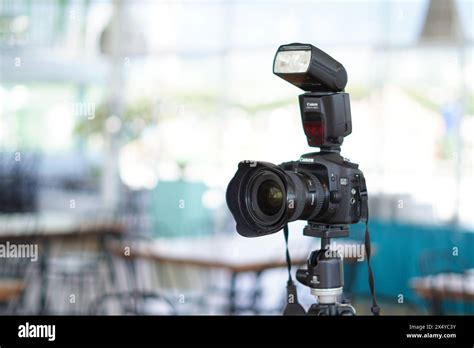 Black Canon DSLR Camera Mounted On A Tripod With An External Flash