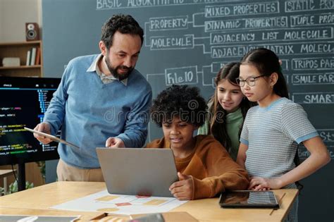 Teacher Engaging Students In Computer Class With Laptops Stock Image