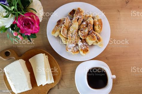 격리 기간 동안 집에서 구운 브러시 우드 수제 디저트 준비 간단한 음식 수제 페타 치즈 나무 테이블 꼭대기에 커피 한 잔 하얀 벽돌 벽과 장미 꽃다발의 배경에 대한 개념 0