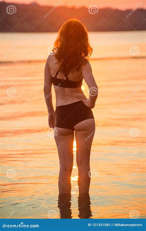 Slender Young Woman In A Bathing Suit On The River Bank Relaxing