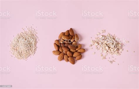 건강한 유기농 아몬드 너트 참깨 및 귀리 플레이크가 분홍색 배경에 흩어져있는 수평 스튜디오 샷 건강한 식생활에 대한 스톡 사진