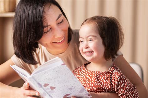 다운 증후군을 앓고있는 행복한 엄마와 딸은 책을 읽고 그림을보고 미소 짓는다 아이에 대한 스톡 사진 및 기타 이미지 아이