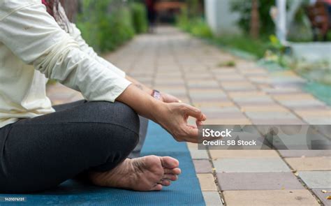 매트에 앉아있는 연꽃 자세에서 요가를하는 여성 Mudra 손 제스처를 닫습니다 배경에 공원과 야외 활동 자연에서 명상을 연습