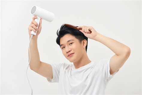 잘 생긴 젊은 남자 건조 그의 머리를 건조 하 고 흰색 배경에 서 있는 동안 미소 남자에 대한 스톡 사진 및 기타 이미지