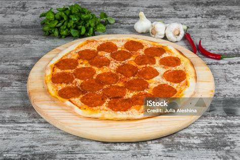 얇은 피자 소시지 살라미 토마토 소스와 로즈마리 밝은 나무 배경에 향신료와 고추 신선한 야채와 녹색 바 질 배경 이탈리아 피자