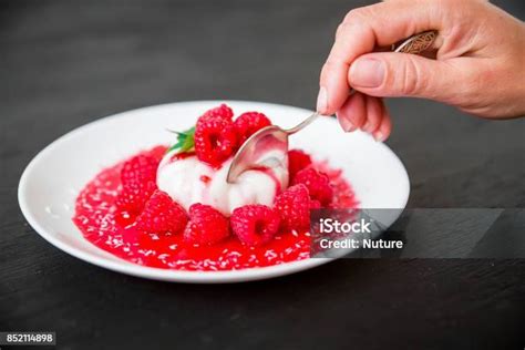 나무 딸기와 어두운 배경에 스푼으로 여성 손 판 나 코타 달콤한 디저트 전통적인 이탈리아 디저트입니다 건강한 생활방식에 대한