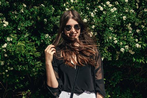 아름 다운 바람 머리 화창한 날에 꽃 덤 불에 재미와 아름 다운 세련 된 Hipster 소녀 Boho 여자 유행 복장에