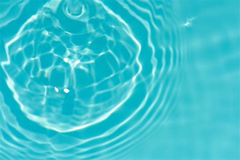 表面に波紋のある青い水ぼかした透明な青色の透明な穏やかな水面テクスチャーと水しぶきと泡の焦点をぼかします輝くパターンテクスチャ背景に水の波