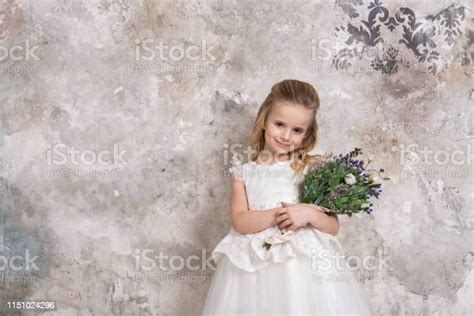 그런 지 벽의 배경에 대해 그녀의 손에 꽃다발 흰 드레스에 작은 매력적인 소녀의 Nportrait 텍스트 공간을 갖춘 스튜디오 촬영 감정에 대한 스톡 사진 및 기타 이미지