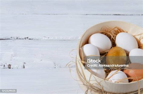 부활절 배경입니다 건초에 있는 체에는 흰 닭 알 황금 알 1개 갈색 이 하나 있습니다 나무 흰색 배경에 체가 서 있다 수평 배경