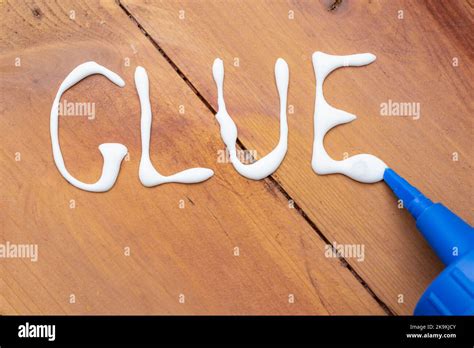 Glue Written On Wood Texture With White Clay Glue Dripping From A Blue