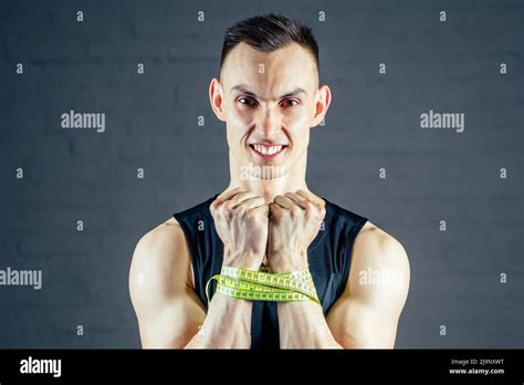 A Young Man Measures His Hand With A Measuring Tape In The Gym On A