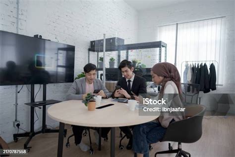 다양한 분야의 전문가 3명이 모여 현대적인 사무실 환경에서 태블릿에 표시되는 데이터 및 차트에 대해 논의하는 비즈니스 미팅 25 29세에 대한 스톡 사진 및 기타 이미지