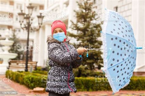의료용 얼굴 마스크를 착용한 어린 소녀는 공원에서 쓰러진 나뭇잎의 오염을 방지합니다 가을에 대한 스톡 사진 및 기타 이미지 가을 건강관리와 의술 걷기 Istock
